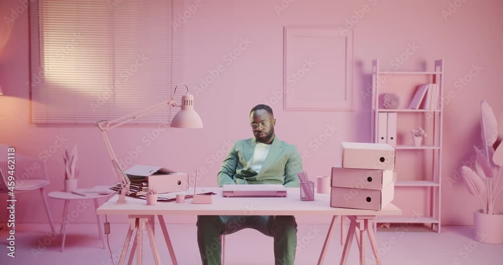 African disappointed burned-out man working hard in pink pastel room ...