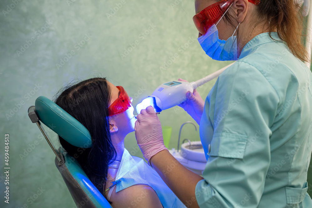 Dentist with ultraviolet lamp in dentistry making whitening to a ...