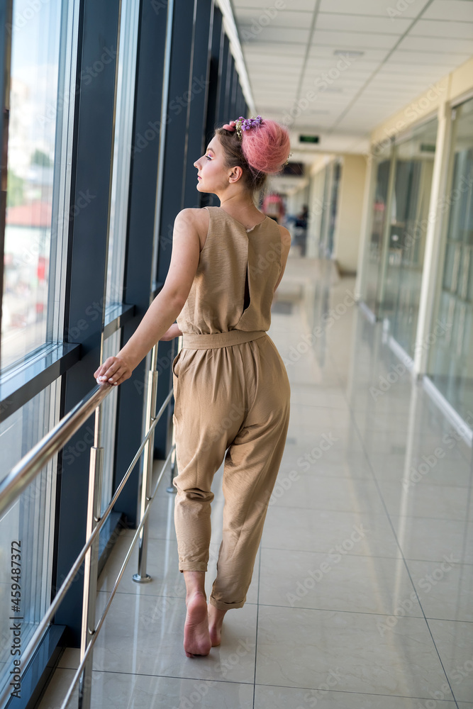 Cute barefoot woman in brown clothes posing inside big business center ...