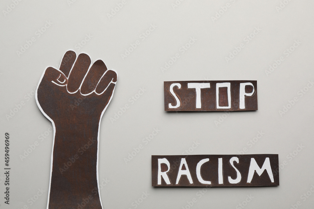 Phrase Stop Racism near paper hand with clenched fist on light ...