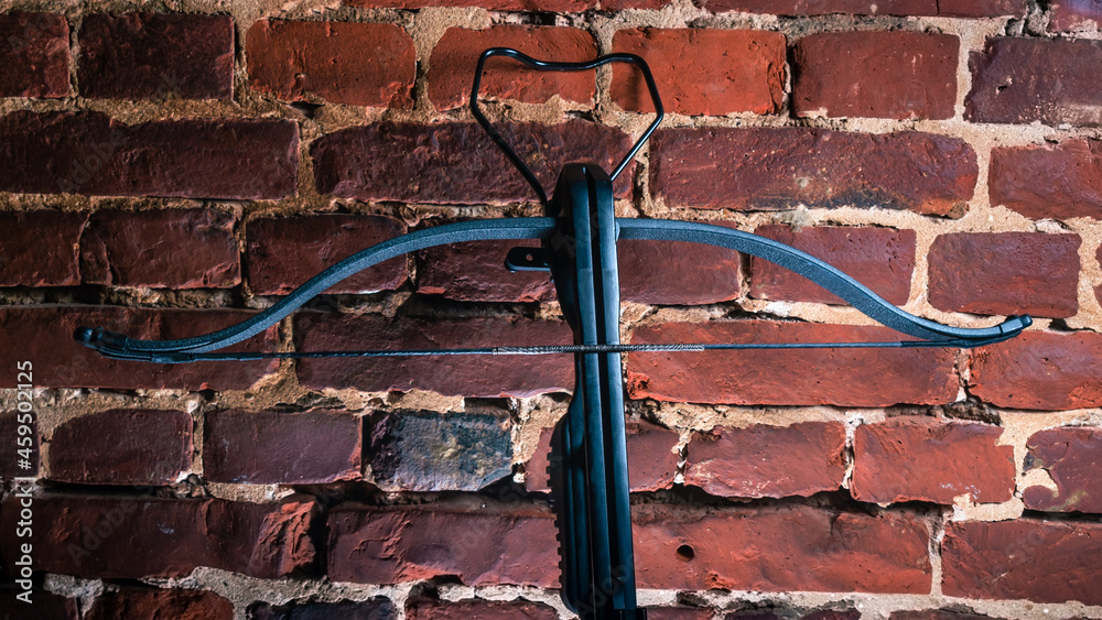 A modern compound crossbow handgun on the red brick wall background ...