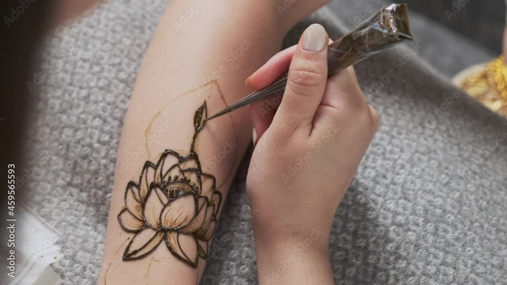 Drawing Mehndi henna tattoo. Process of applying mehndi on female hands ...
