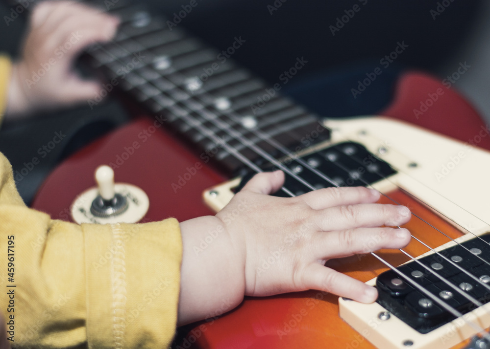 Baby playing the electric guitar. Baby hands on guitar strings ...