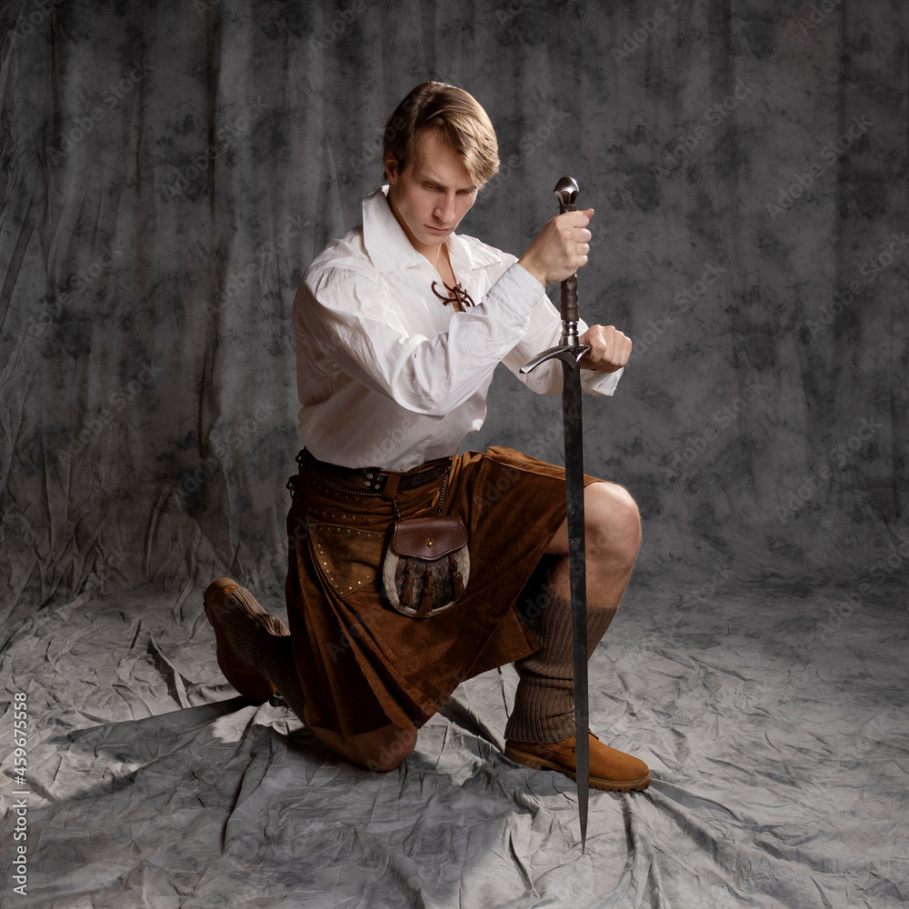 The Scottish knight knelt, took an oath, concept. A young man in a kilt ...