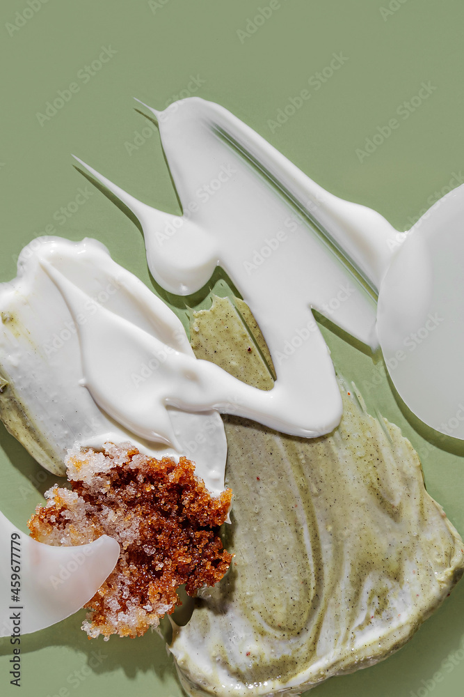 Various cosmetic mask, creams, serum, scrub and lotion smear on a green ...