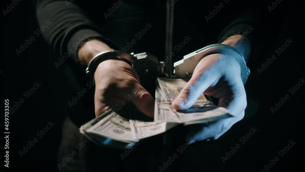Man's hands in handcuffs are holding a bribe. Arrested criminal or ...