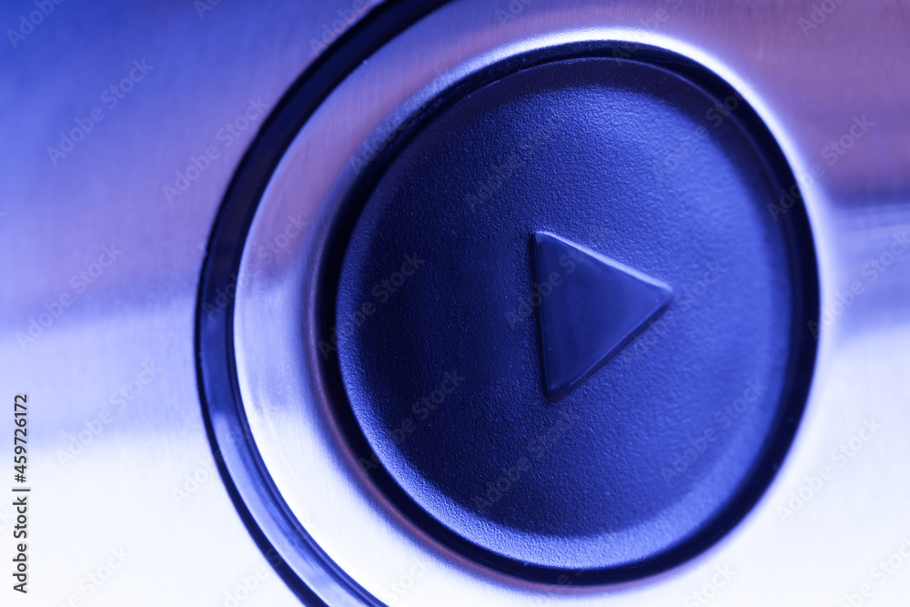 Round embossed play button on a light polished metal surface of a ...