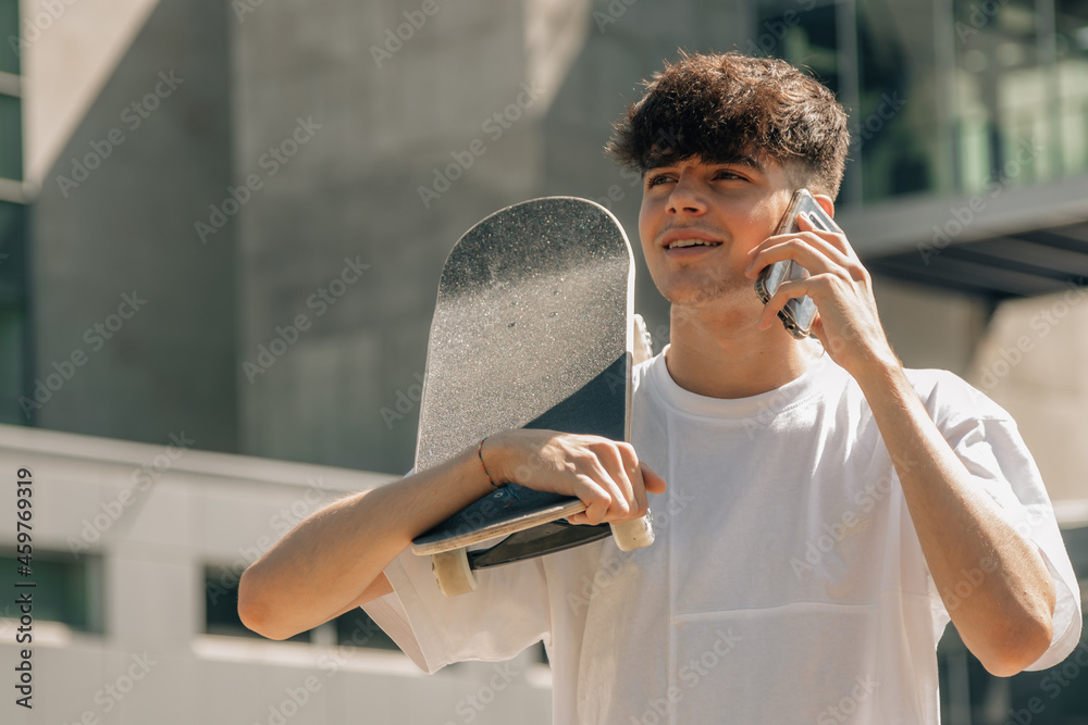 teenage boy talking on mobile phone in the street with skateboard Stock ...