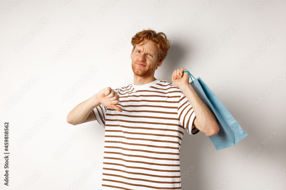 Disappointed young man with red hair and beard showing thumbs-down ...