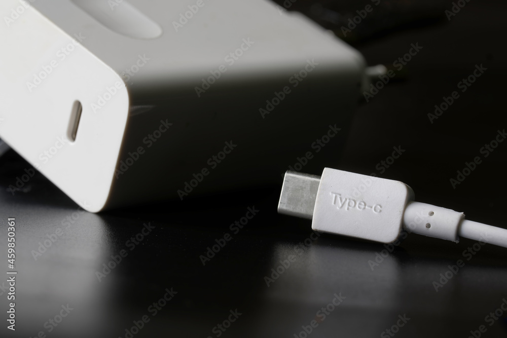 White usb type-c plug on a black background next to the white power ...