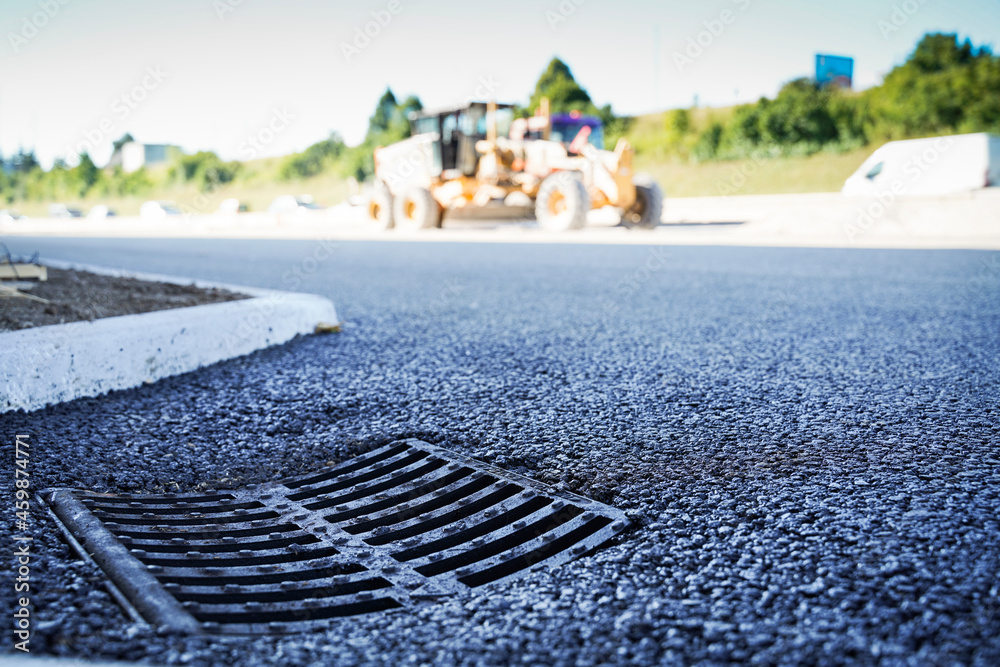 Sewer grate constructing drain, asphalt road, road grader and dump ...
