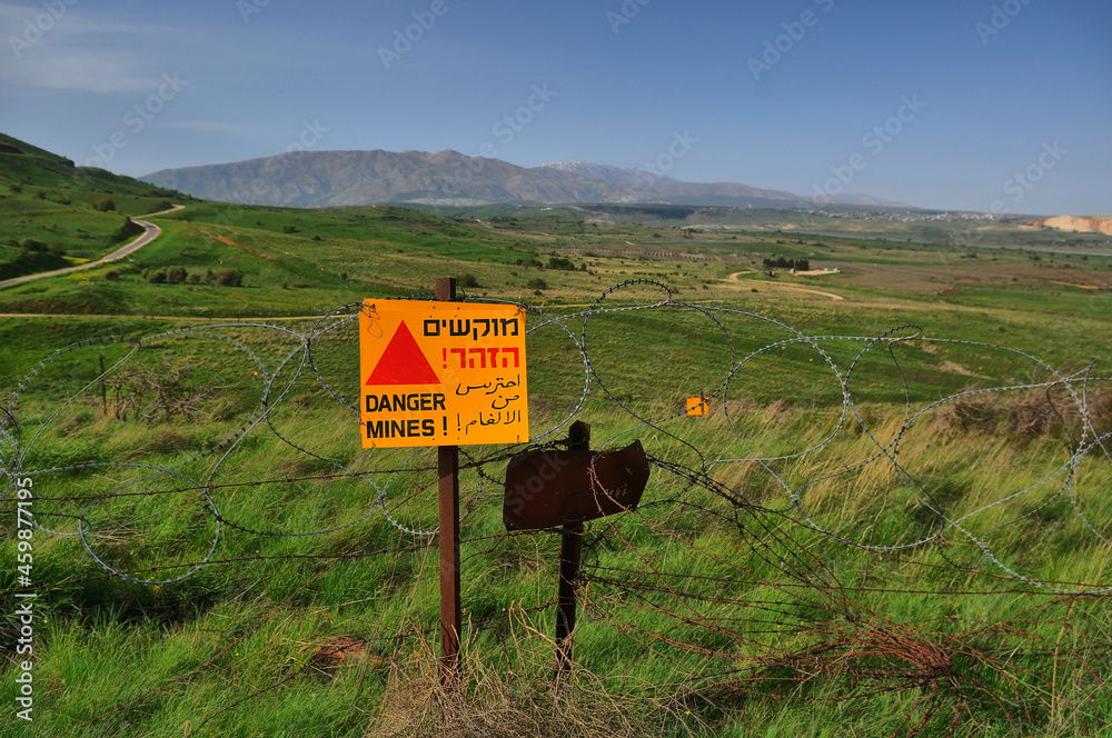 Minefield danger mines yellow warning sign on a barbed wire fence in ...