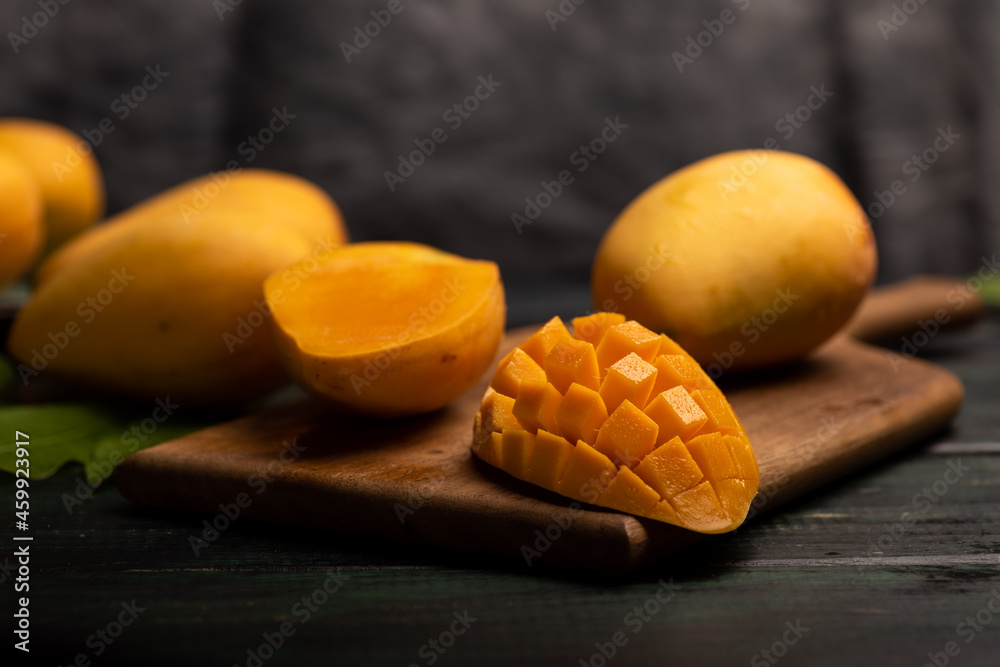 Cut and complete mangoes on the chopping board Stock Photo | Adobe Stock