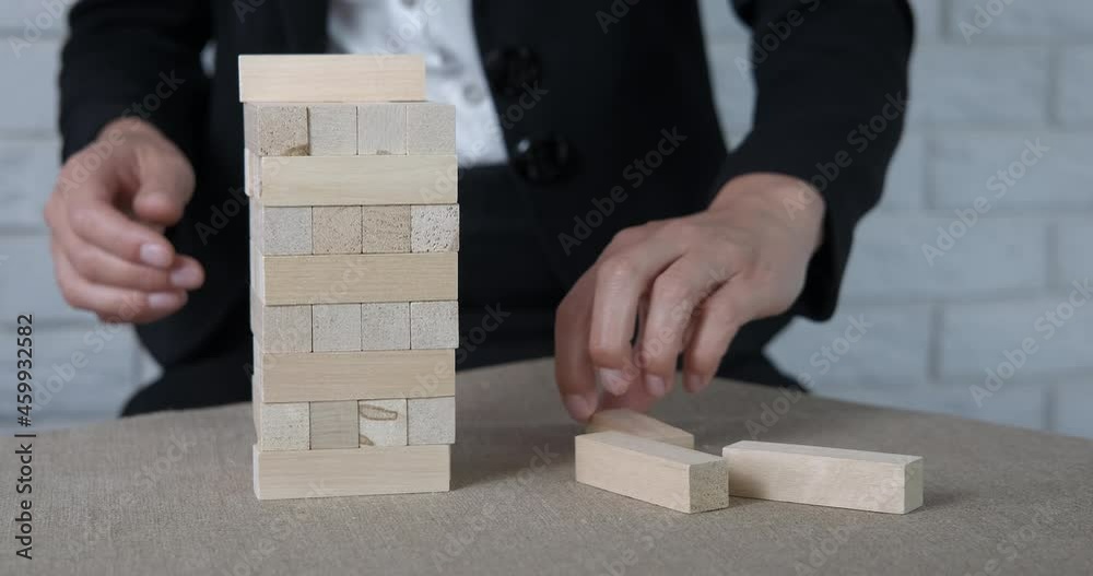Businessman with construction blocks. A man makes a layout with wooden ...