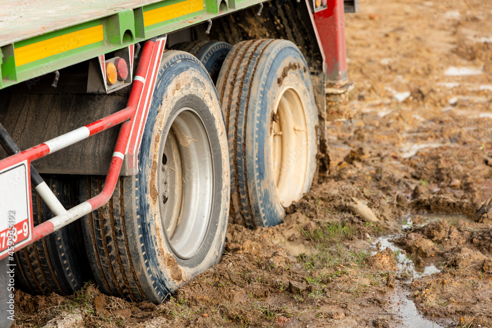 Wheel of a heavy truck lorry stuck in deep mud soft ground. Muddy and ...