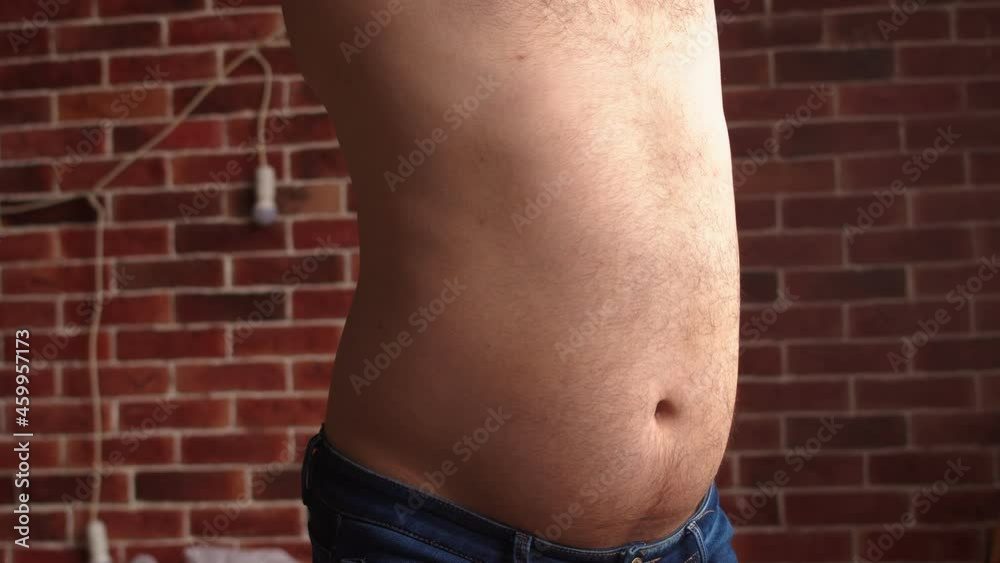 Man takes off black T-shirt, exposing his fat stomach, against the ...
