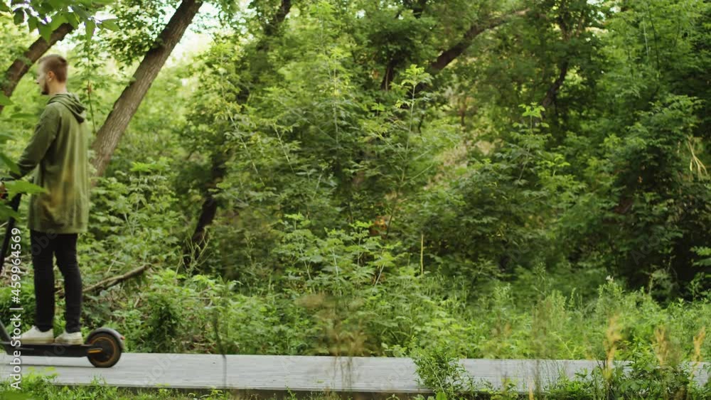 Woman and man drive along path in park on electric scooters, side view ...