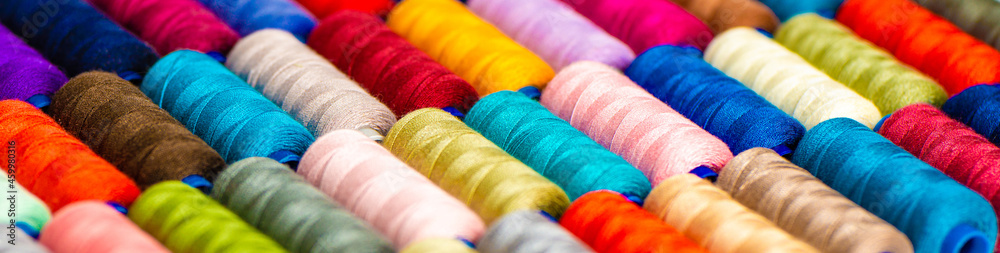 Multi-colored sewing threads laid out in a row. Bright background ...