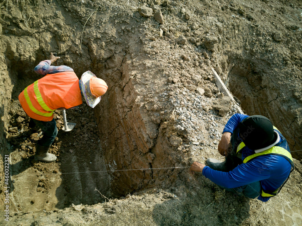 two workman is digging and sitting on ground soil, worker is dig for ...