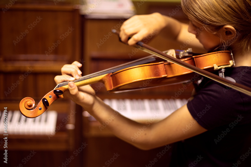 blurry left hand of a young violinist presses the strings on the violin ...
