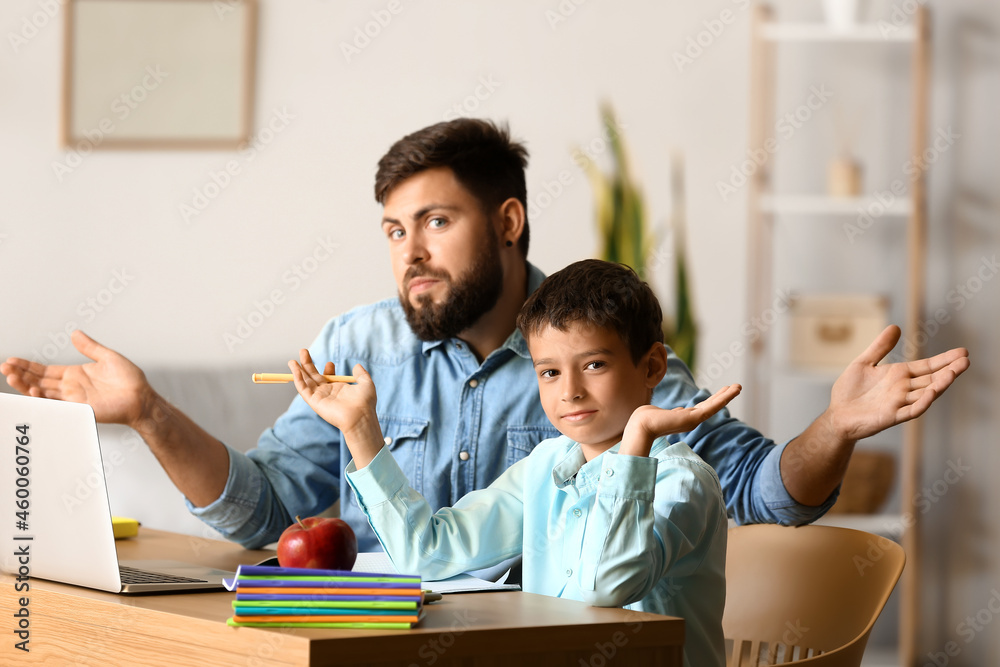 Confused little boy and his father doing lessons at home Stock Photo ...