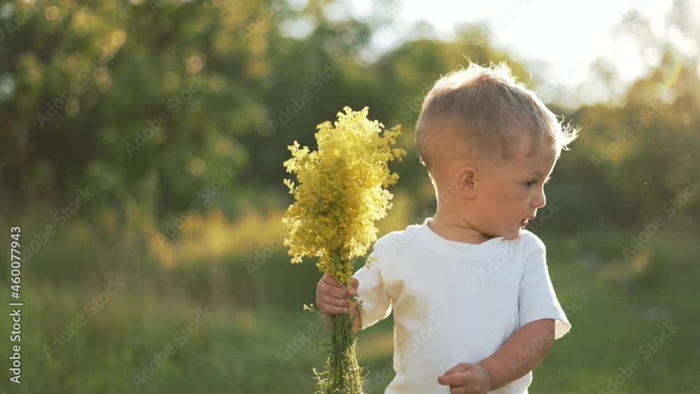 Happy kid in flower field. Child with bouquet of flowers.Boy walks ...