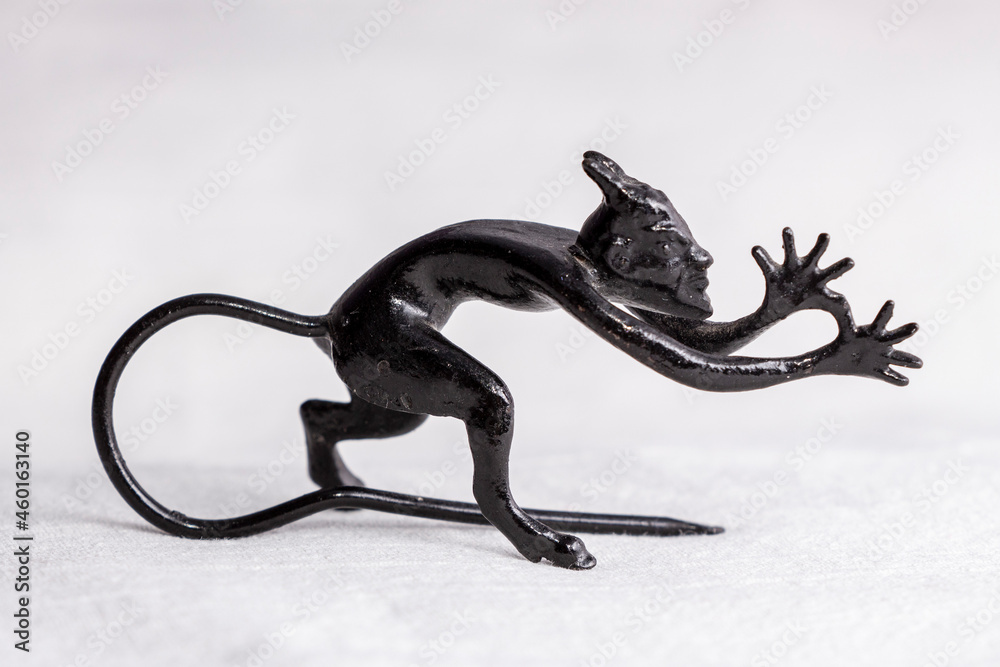 Metal sculpture of a devil grimacing. Devil with hooves, tail and horns ...