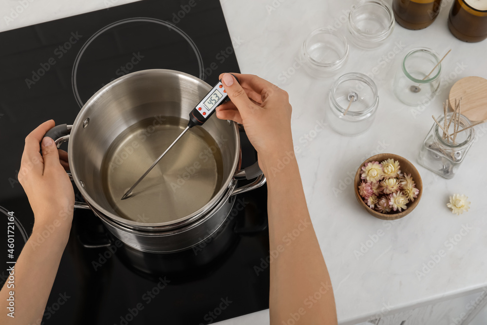 Foto de Woman measuring temperature of melted wax in kitchen, closeup ...