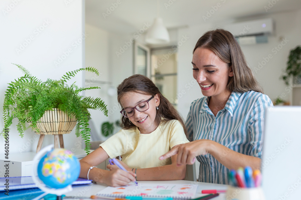 Cute girl with mother doing homework at home. A mother helps her little ...