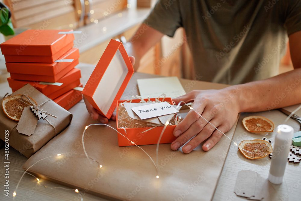 Hands of young millennial worker packing Christmas gift boxes for ...