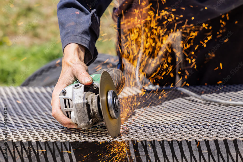 An image if hands of a female welder holding an electronic disc grinder ...