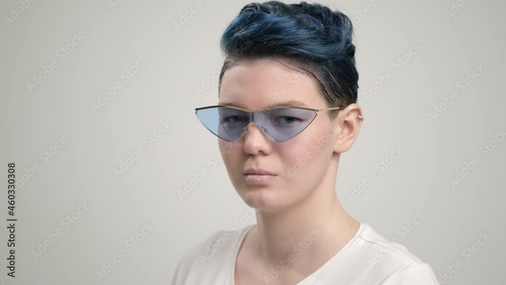 A young girl with a short pixie haircut and dark blue hair in a white T ...