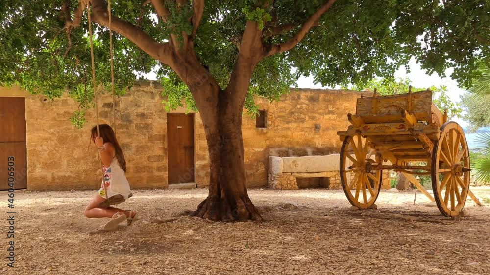 Lttle girl have fun on tree swing with Sicilian cart or carretto ...
