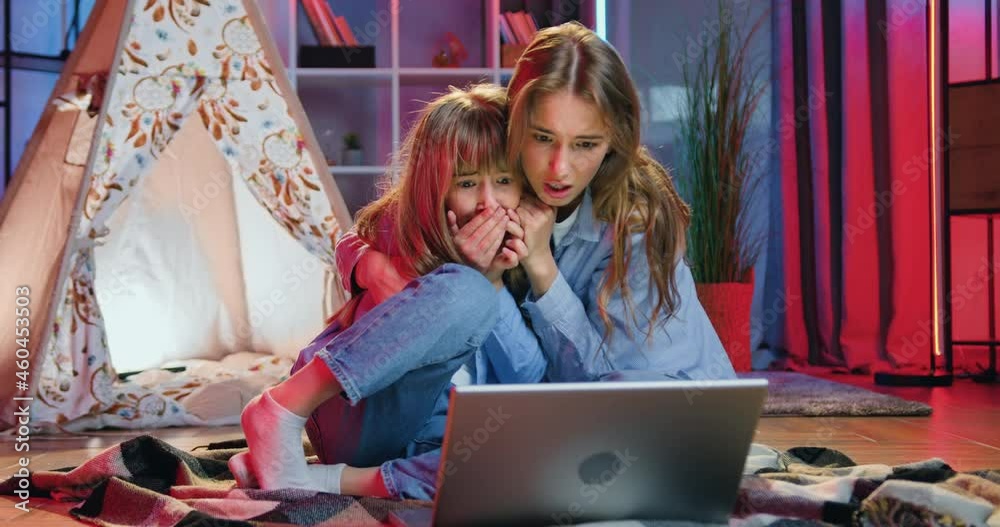 Beautiful scared two sisters,younger and eldest,watching horror on ...