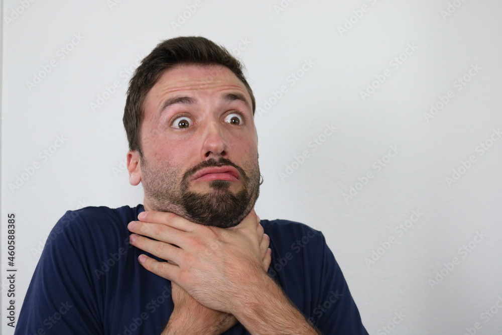 Young man choking, holding his neck with both hands Photos | Adobe Stock