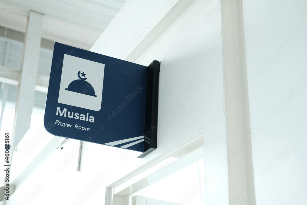 mushola direction or a prayer room sign is hanging on a white wall. the ...