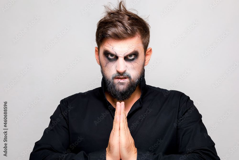 Scary undead-style makeup for Halloween on a bearded man who shows ...