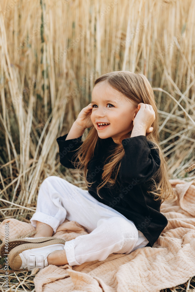 pretty 3-year-old girl walks and poses for a photo in a wheat field at ...