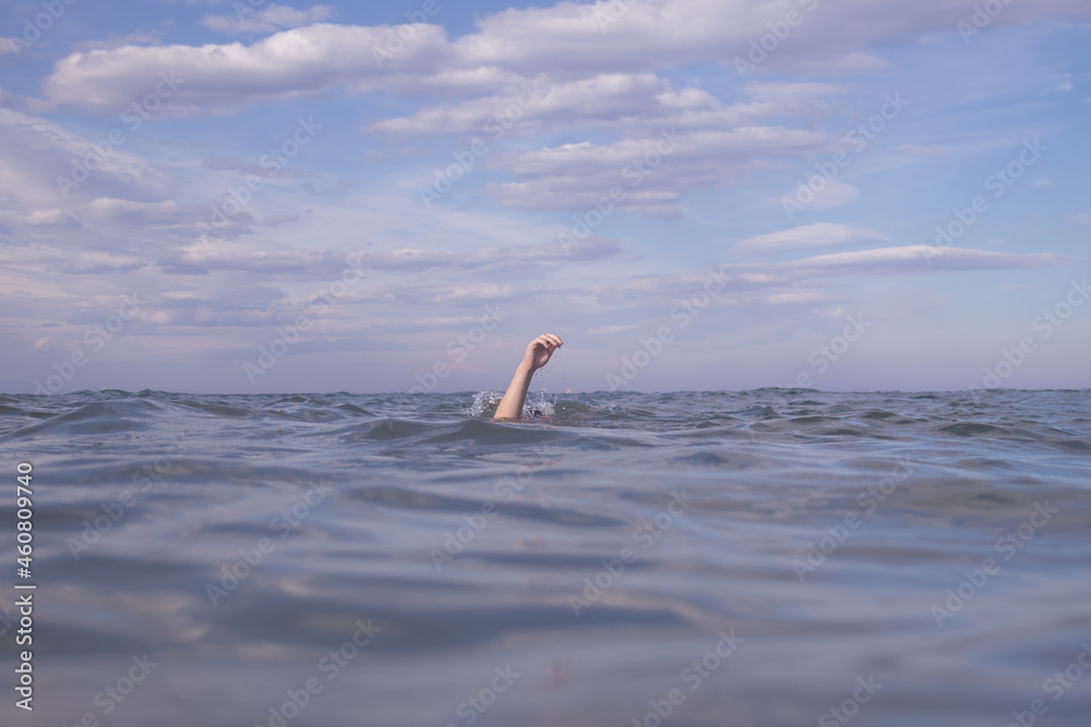 Person submerged on a beach with hand out pretending to be drowning ...