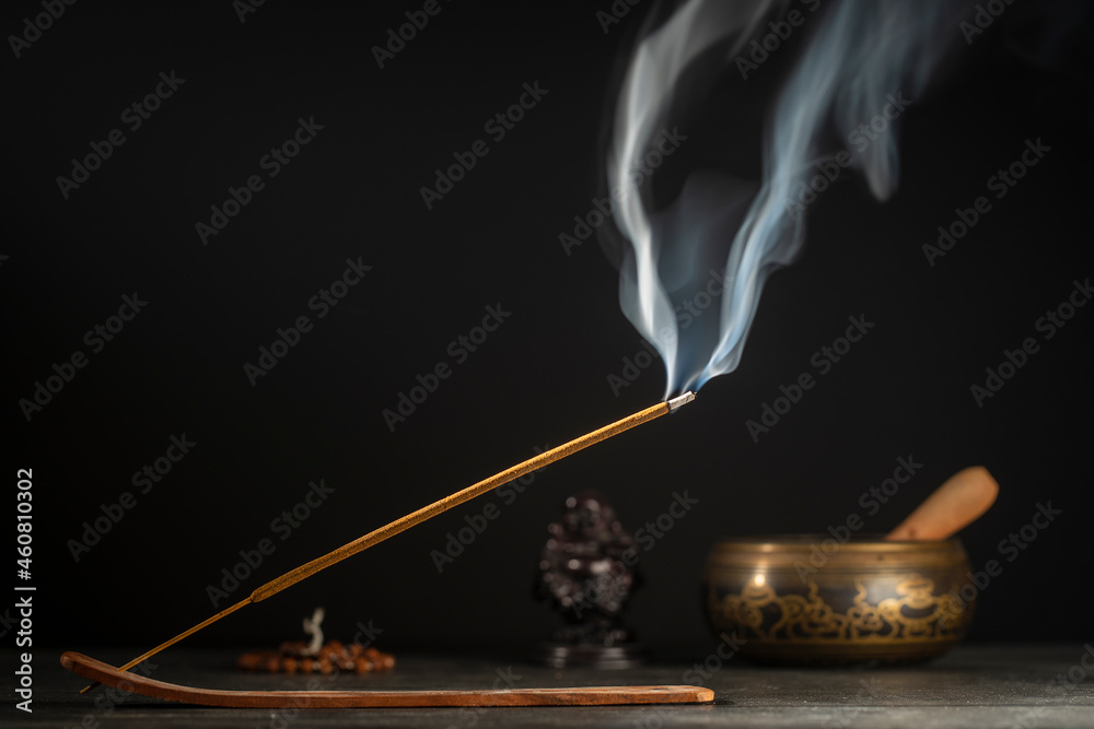 Asian incense stick in stick holder burning with smoke on black ...