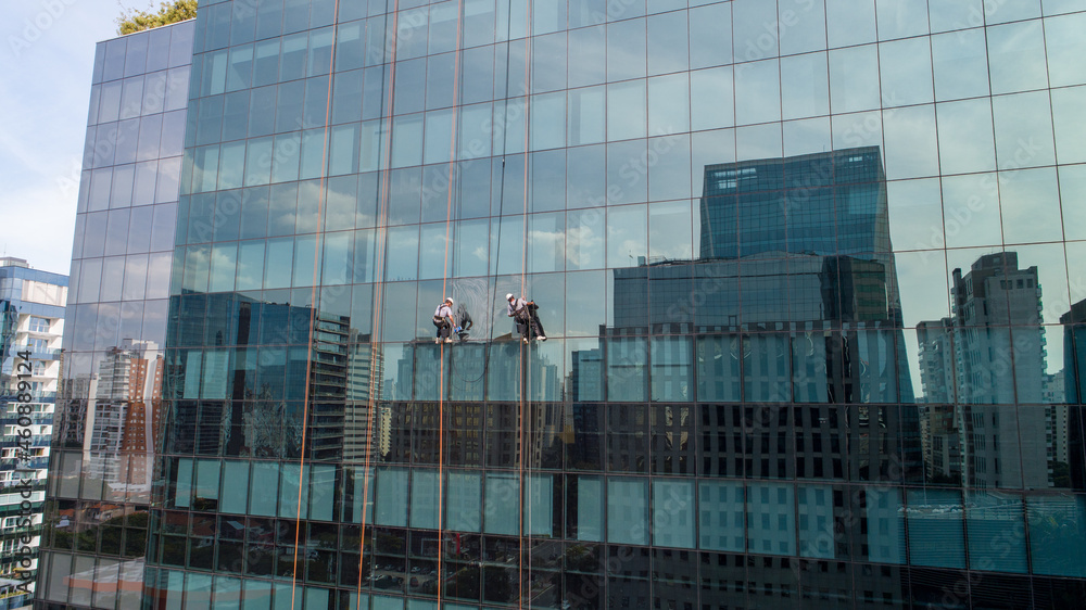 Two male workers with safety equipment at heights. Cleaning up a tall ...