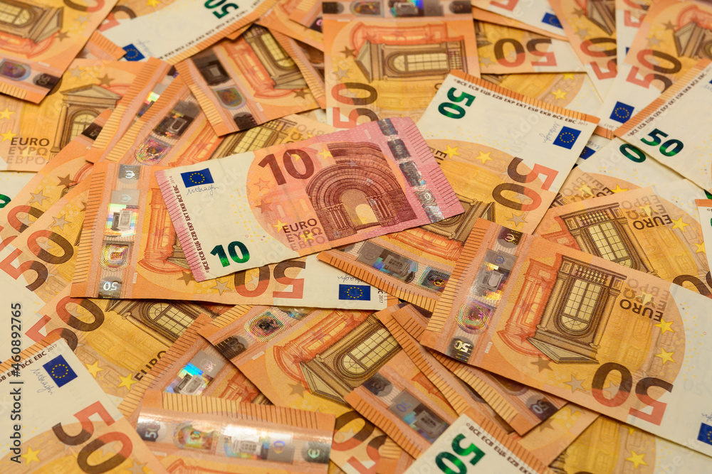 Banknotes in denominations of 50 and 10 euros are scattered randomly on ...