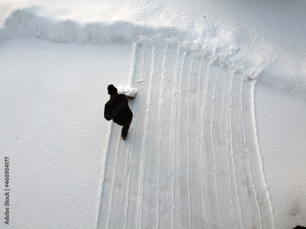 op down view of man shoveling a second time because of continuously ...