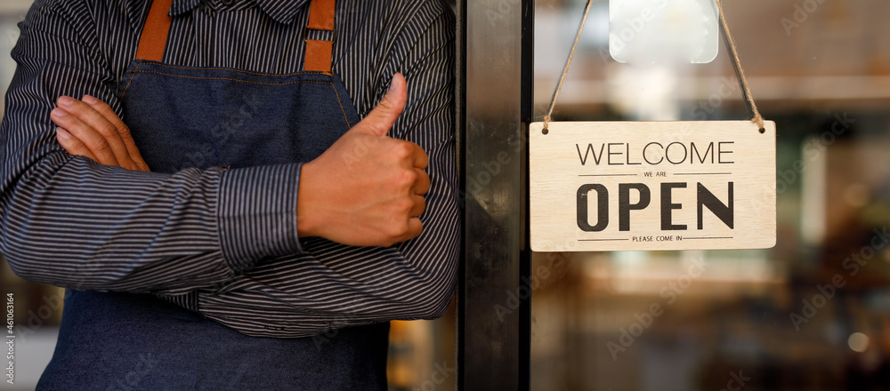 Close up of Store owner turning open sign broad through the door glass ...