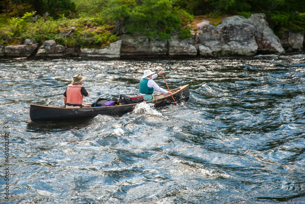 Poster A fully loaded canoe with two paddlers shooting a set of rapids ...