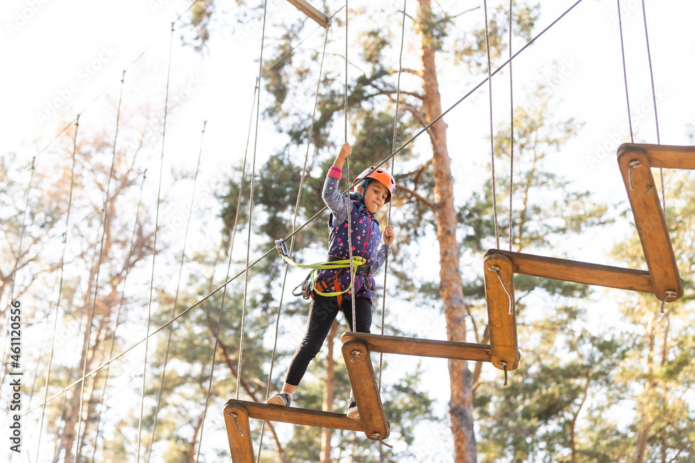 Child in forest adventure park. Kids climb on high rope trail. Agility ...