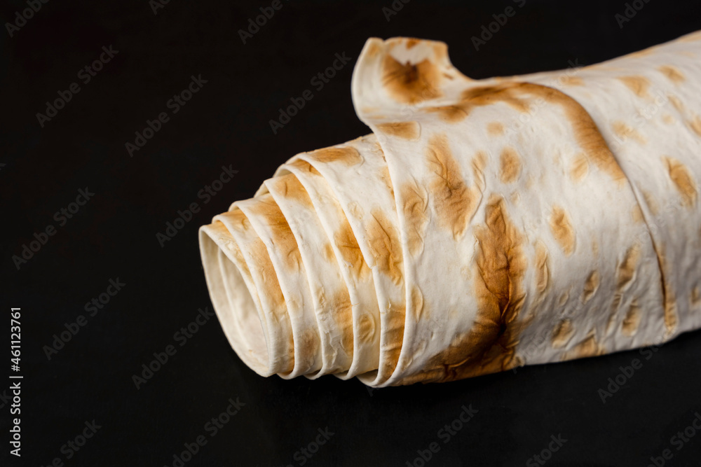 Lavash rolled on a black background, thin traditional oriental bread ...