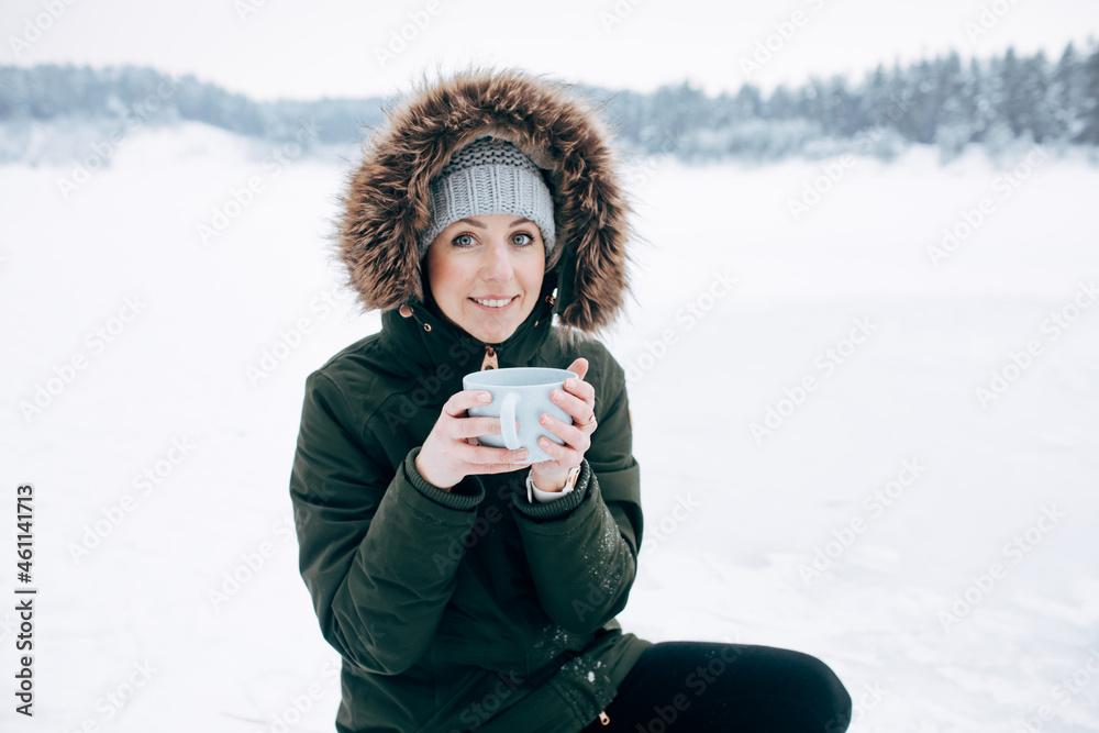 Beautiful young female smiling and drinking tea in nature Winter ...