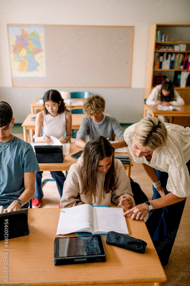 Female professor helping girl in high school classroom Stock Photo ...