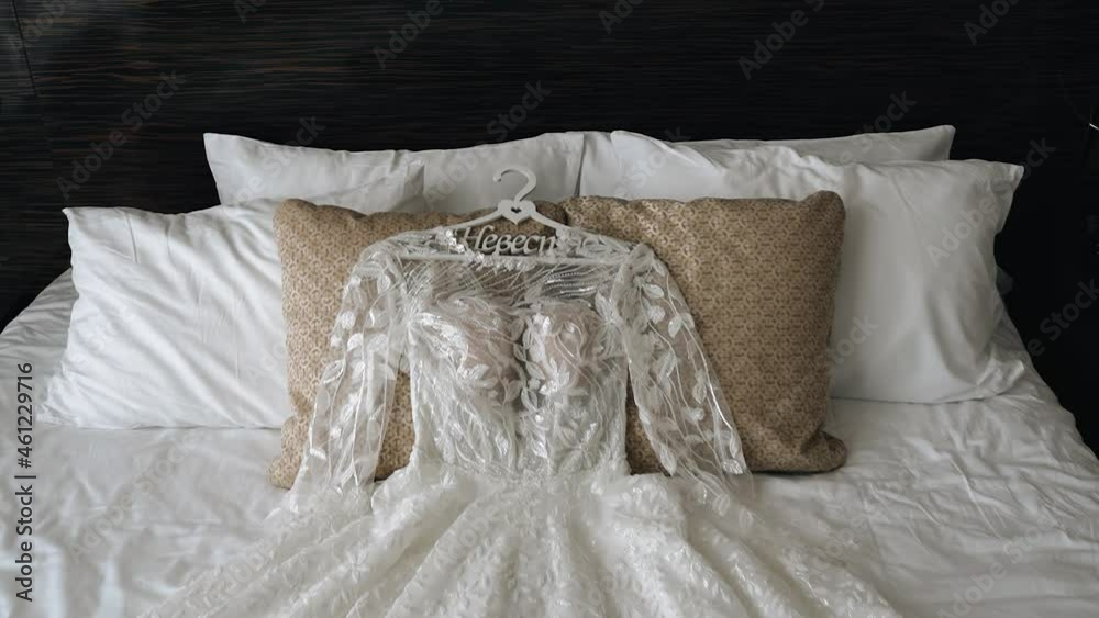 A white wedding dress is lying on the bed. Shooting an object in motion ...